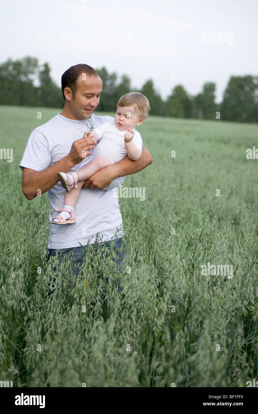 A father carrying his baby daughter in a field Stock Photo - Alamy