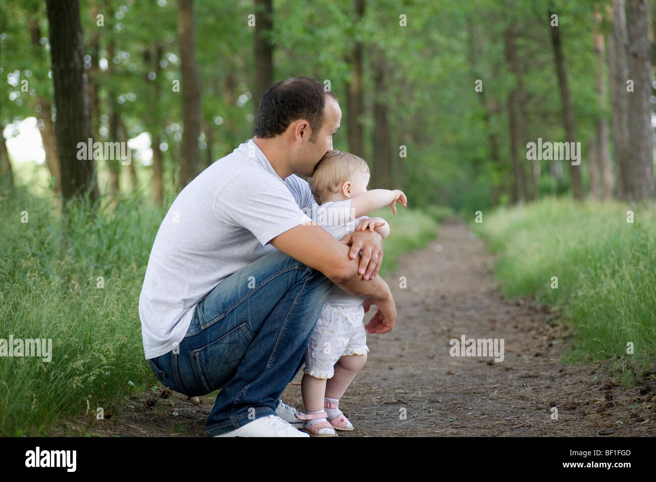 A father crouching with his baby daughter on a rural path Stock Photo ...