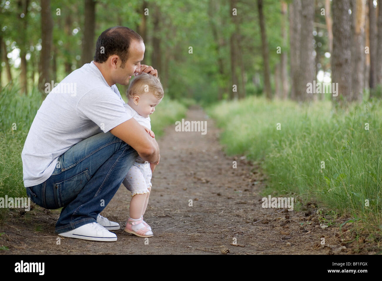 A father crouching with his baby daughter on a rural path Stock Photo ...