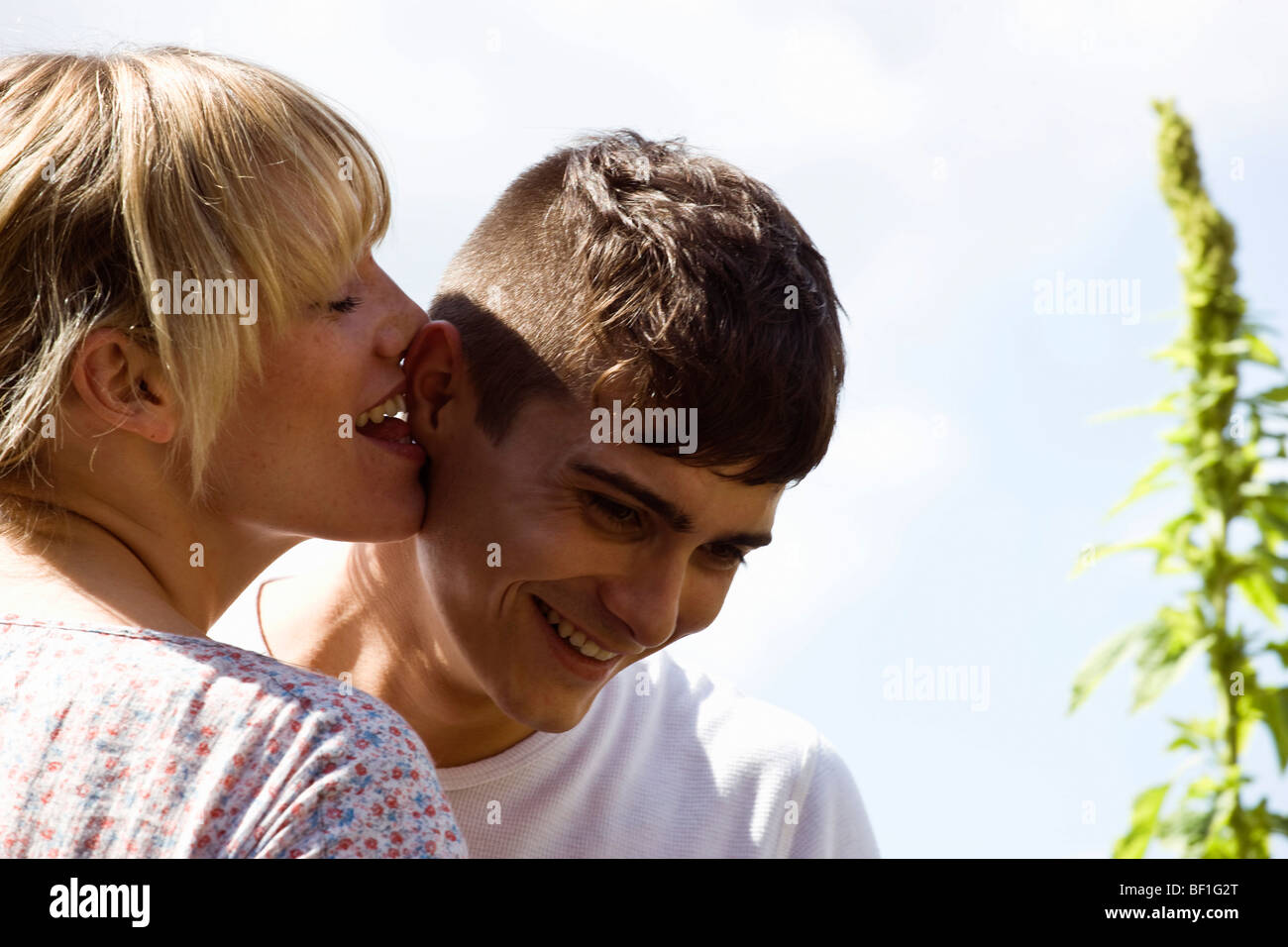 A young woman playfully licking a young man's ear Stock Photo - Alamy