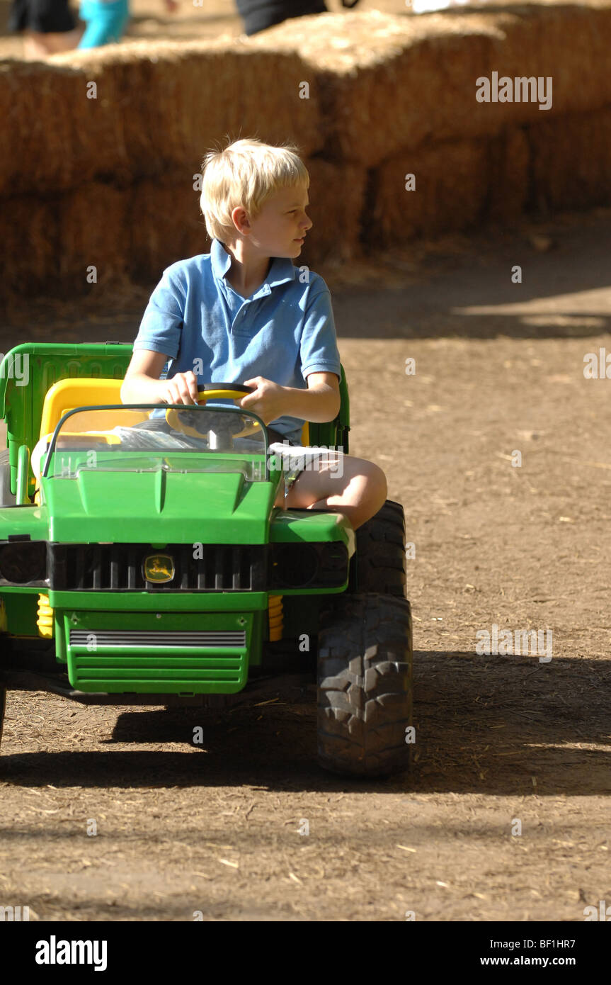 Young children enjoy driving toy-tractors at on a makeshift tractor ...