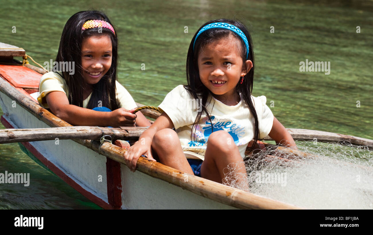 Portrait of two Filipino girls sitting in a traditional canoe (banca ...