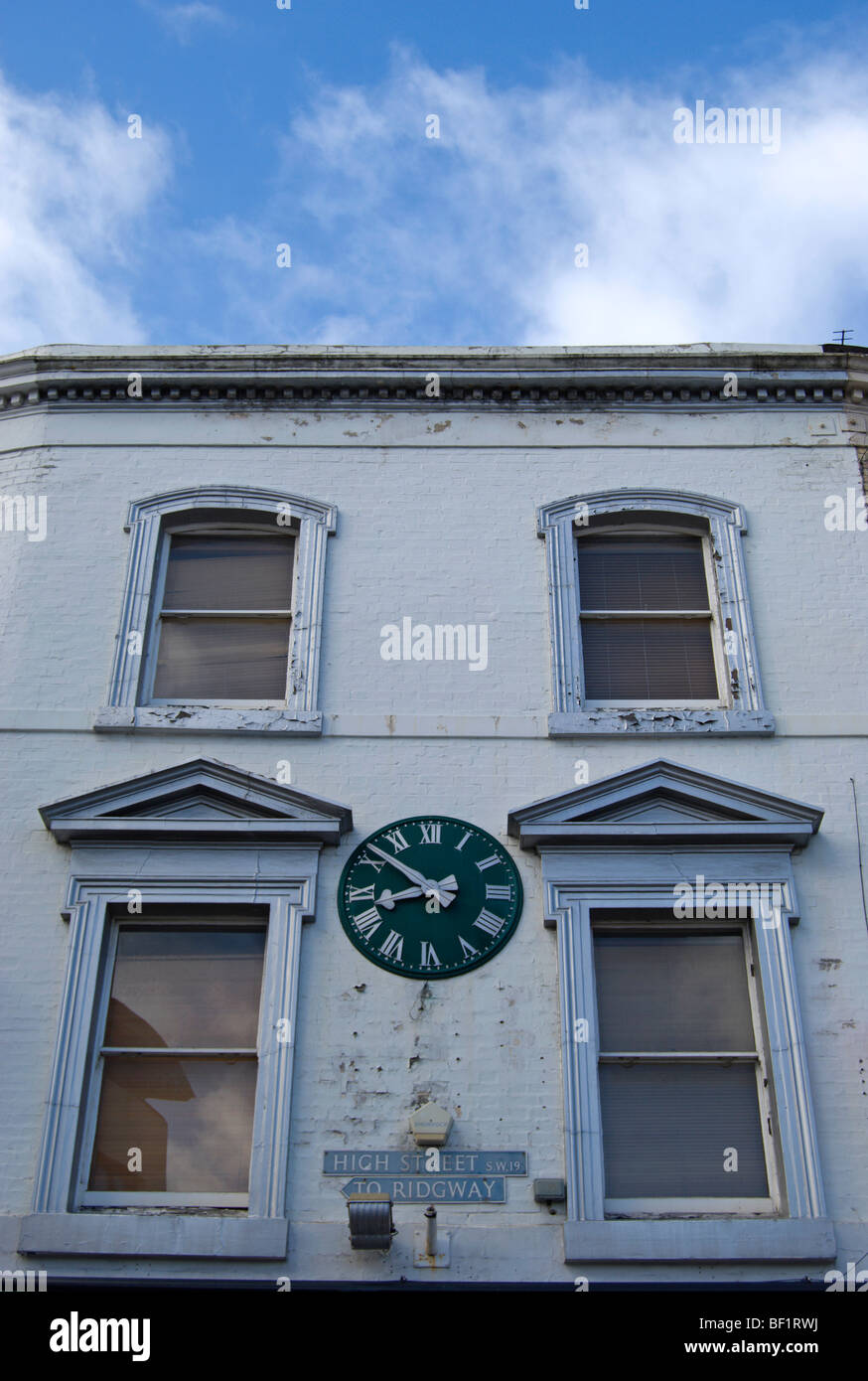 exterior of rundown buiilding with prominent wall clock, in wimbledon ...