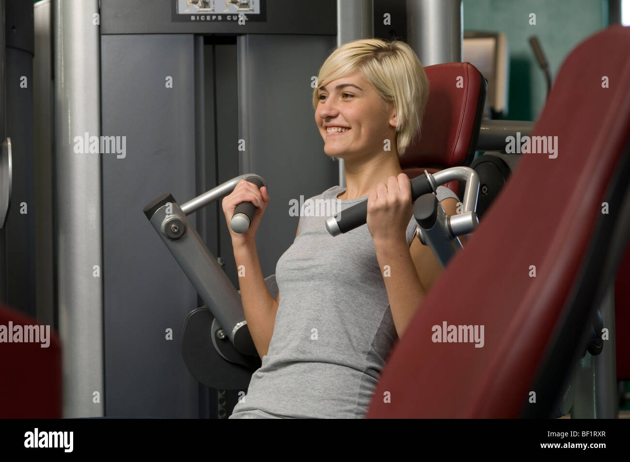 Young woman using equipment in a gym Stock Photo - Alamy