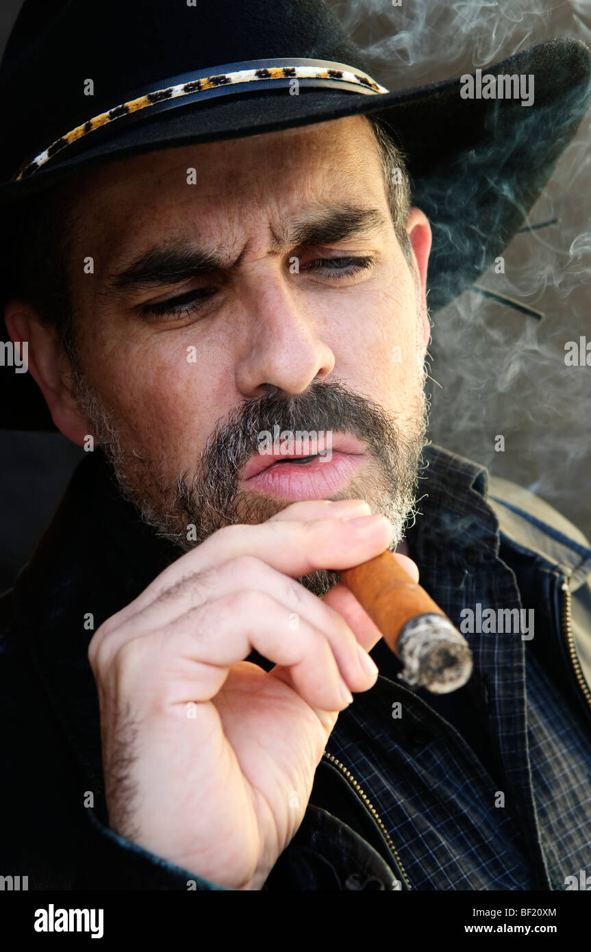 Man with beard in cowboy hat smoking cigar Stock Photo - Alamy