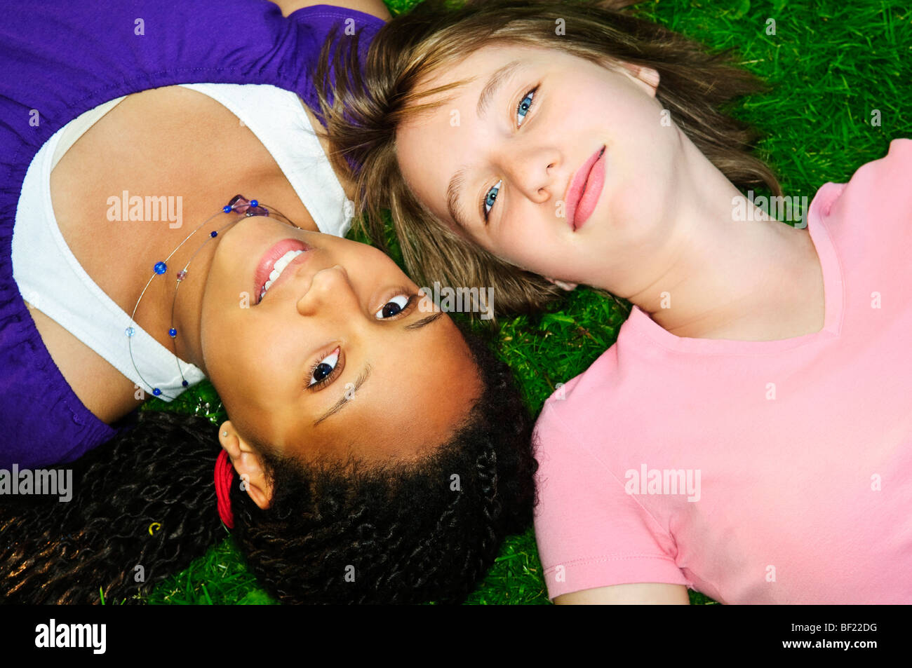 Two teenage girls laying on grass looking up Stock Photo - Alamy