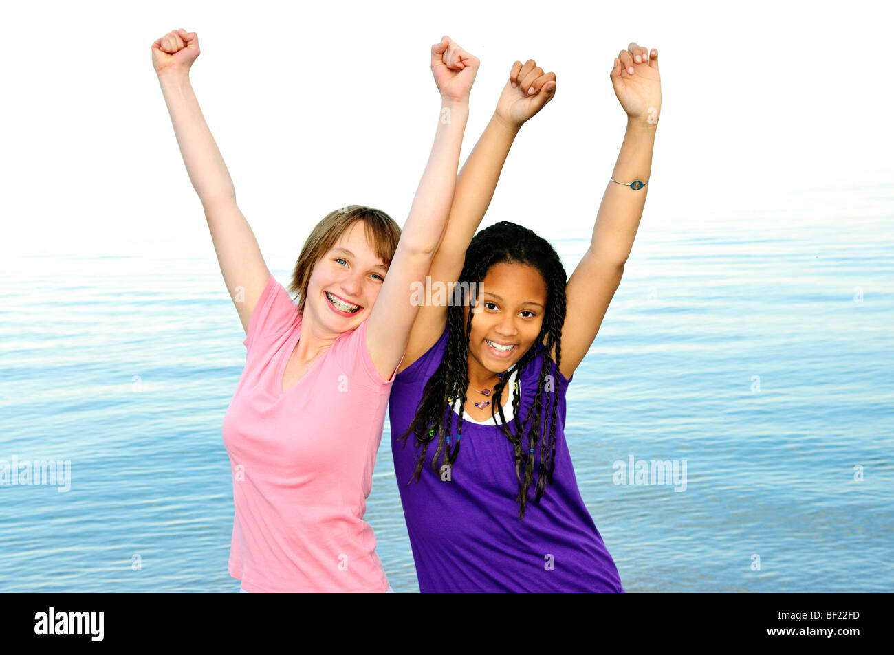 Portrait of two teenage girl friends raising arms Stock Photo - Alamy