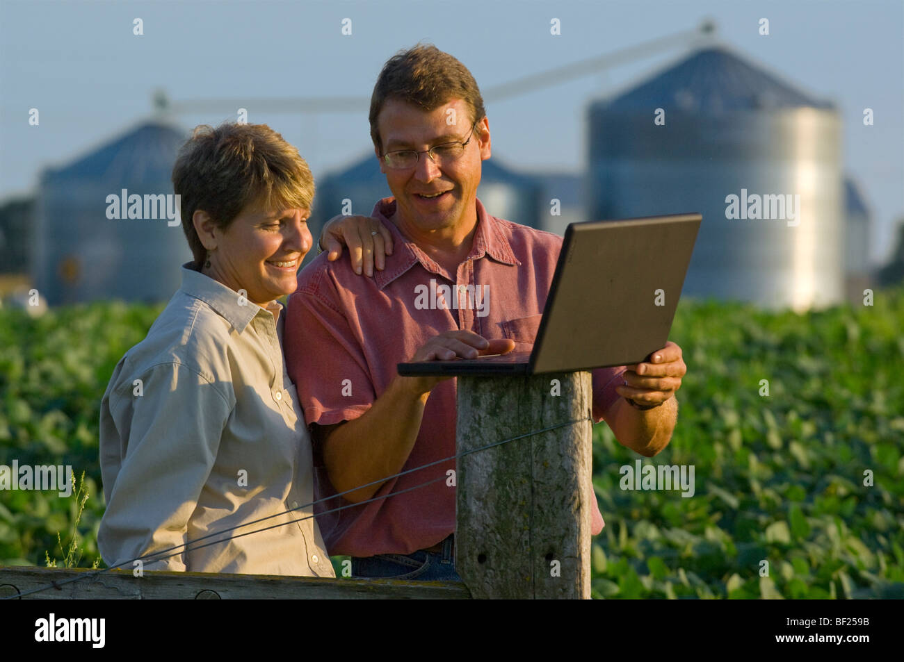 Husband and wife farmers in their soybean field input crop data into ...