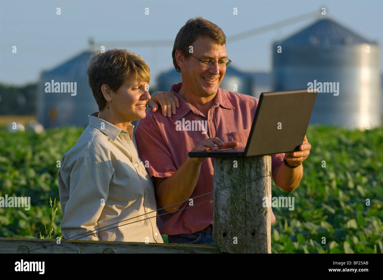 Husband and wife farmers in their soybean field input crop data into ...