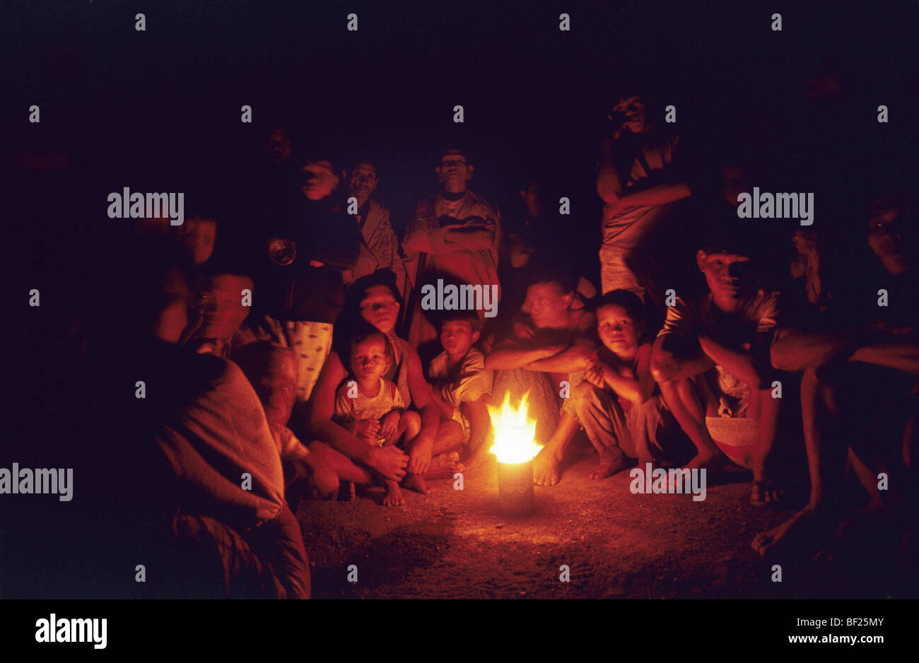 Natives community group at nighttime, sitting around oil burner fire ...