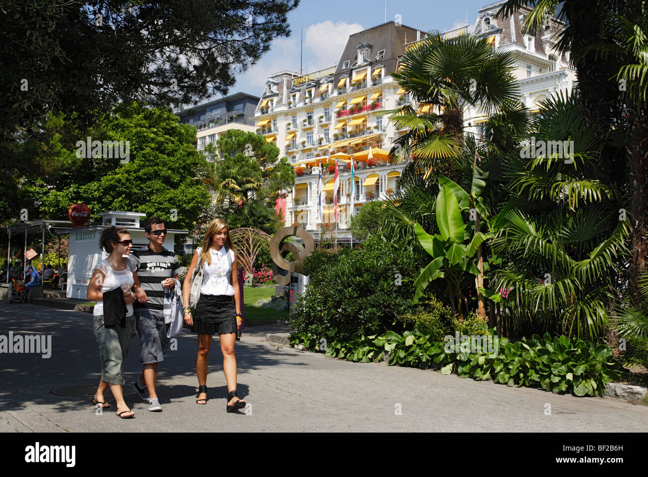 Young people walking along promenade, Grand Hotel Suisse in background ...