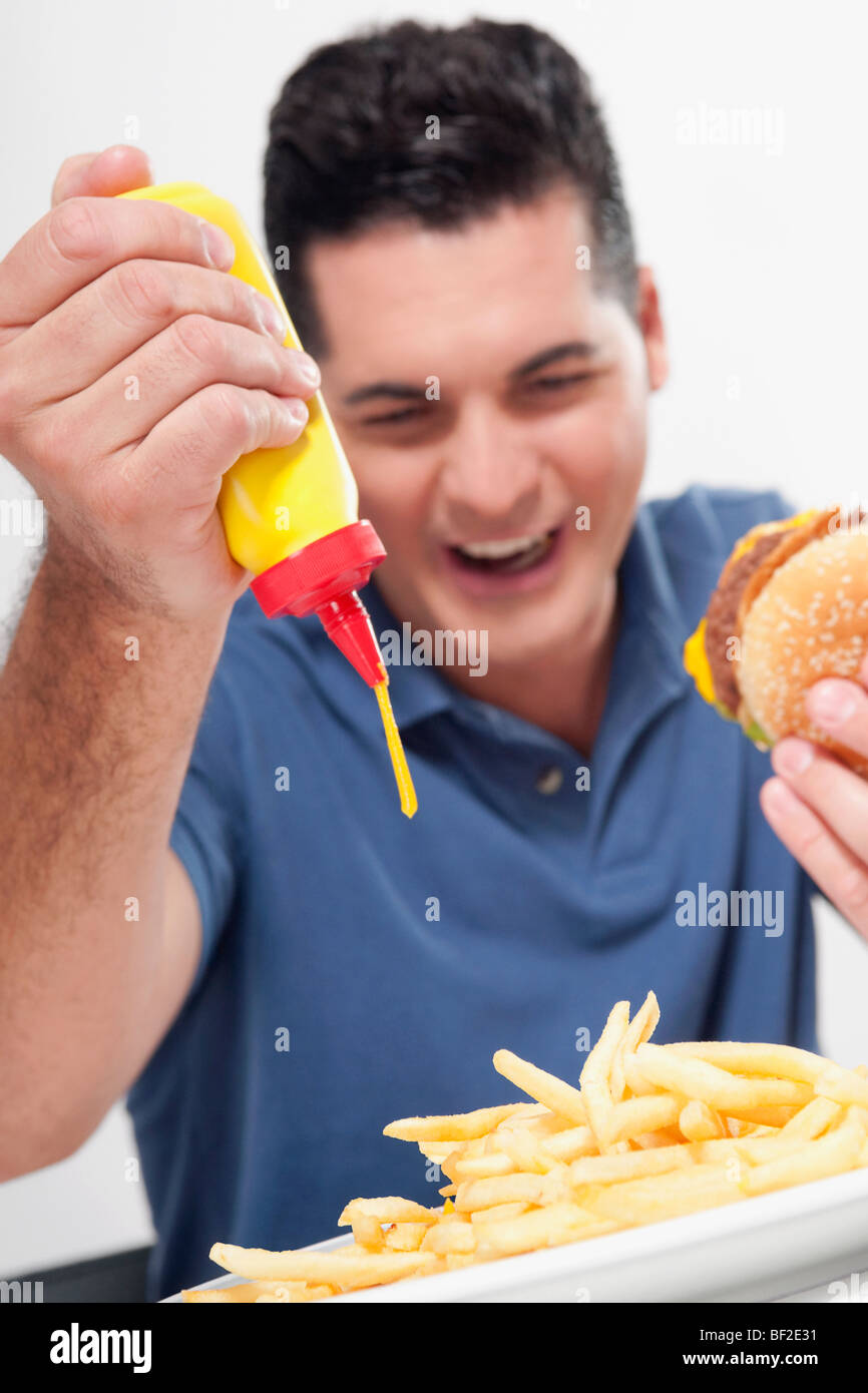 Man squeezing mustard on fries Stock Photo - Alamy