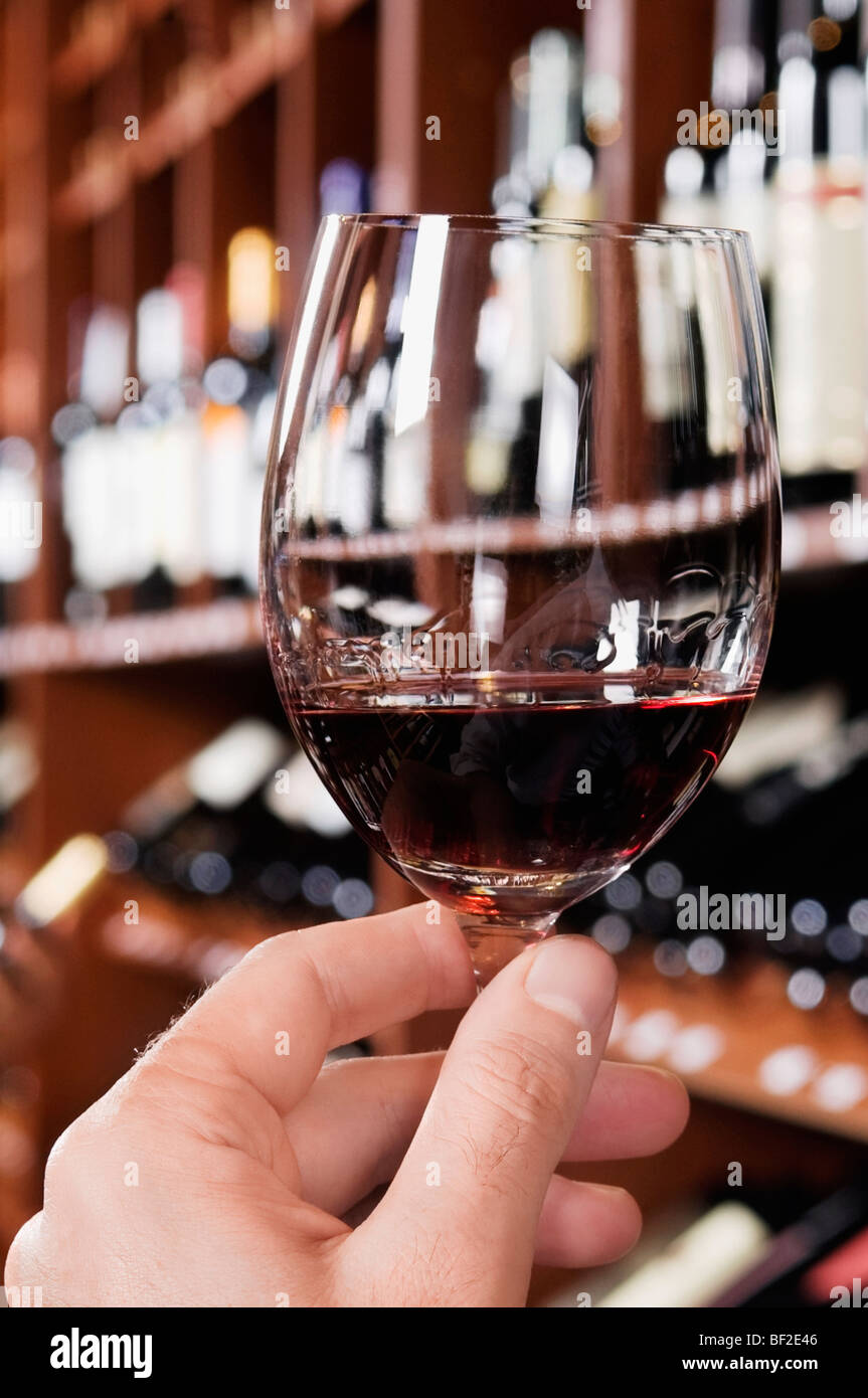 Man's hand holding a wine glass in a bar Stock Photo - Alamy