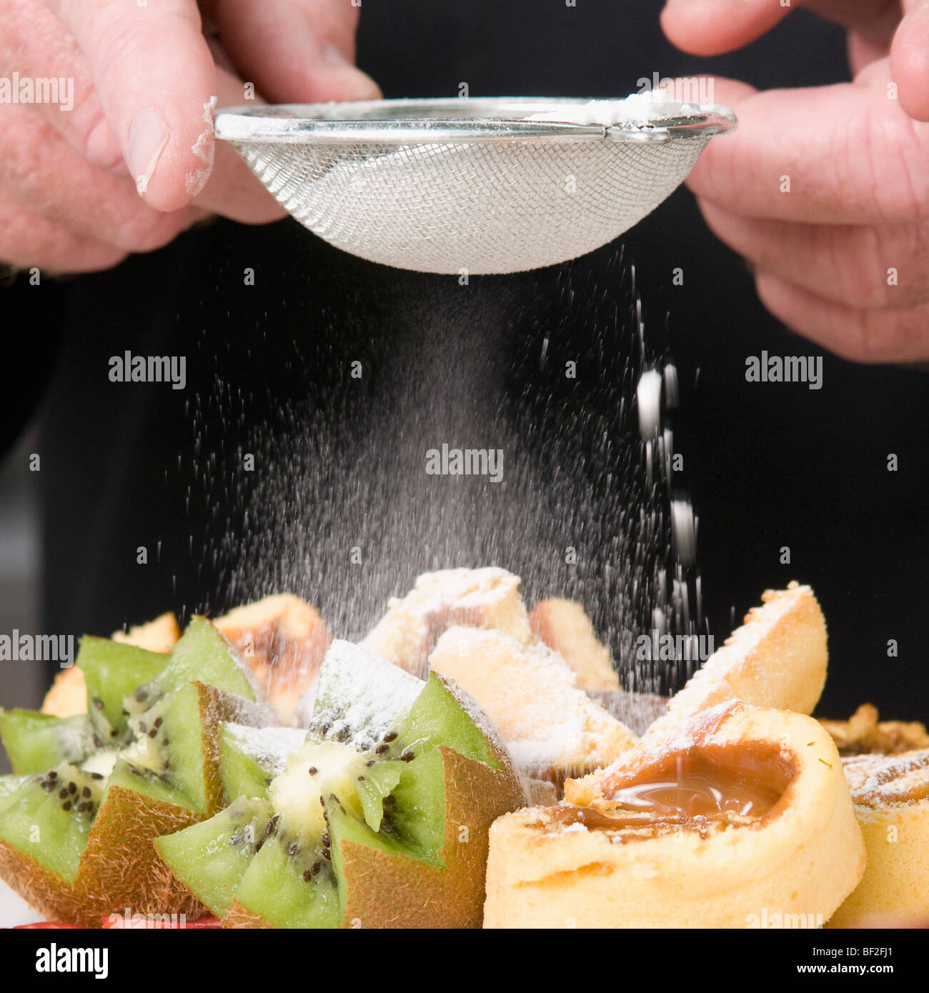 Mid section view of a chef sieving sugar over fruit salad Stock Photo ...