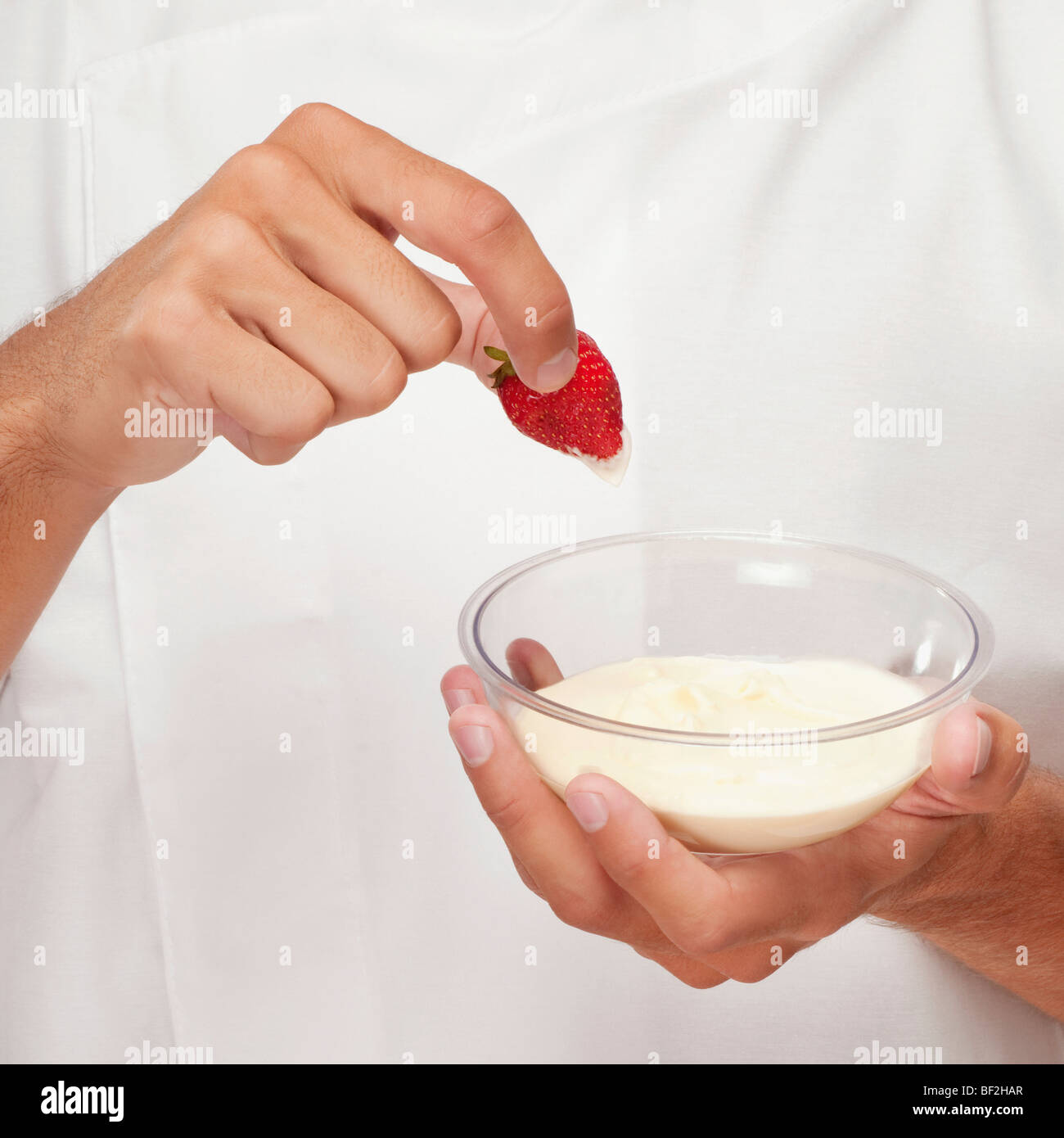 Man dipping a strawberry in cream Stock Photo - Alamy