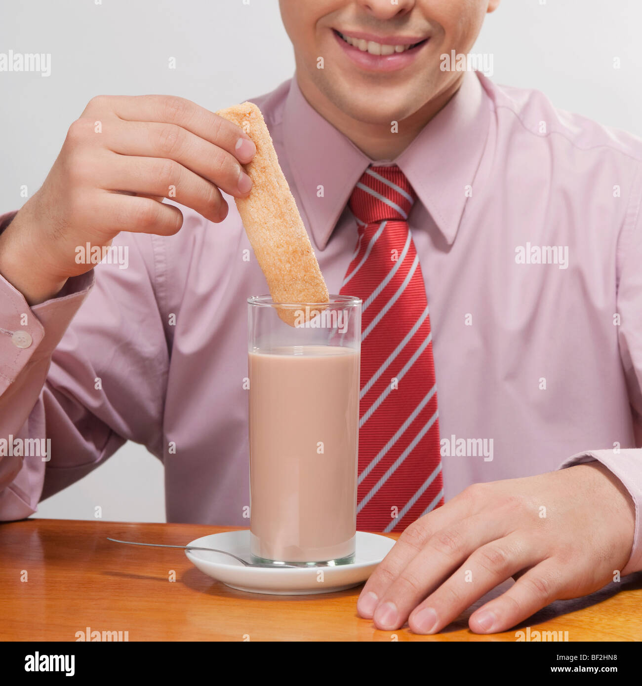 Businessman dipping a wafer into milk Stock Photo - Alamy