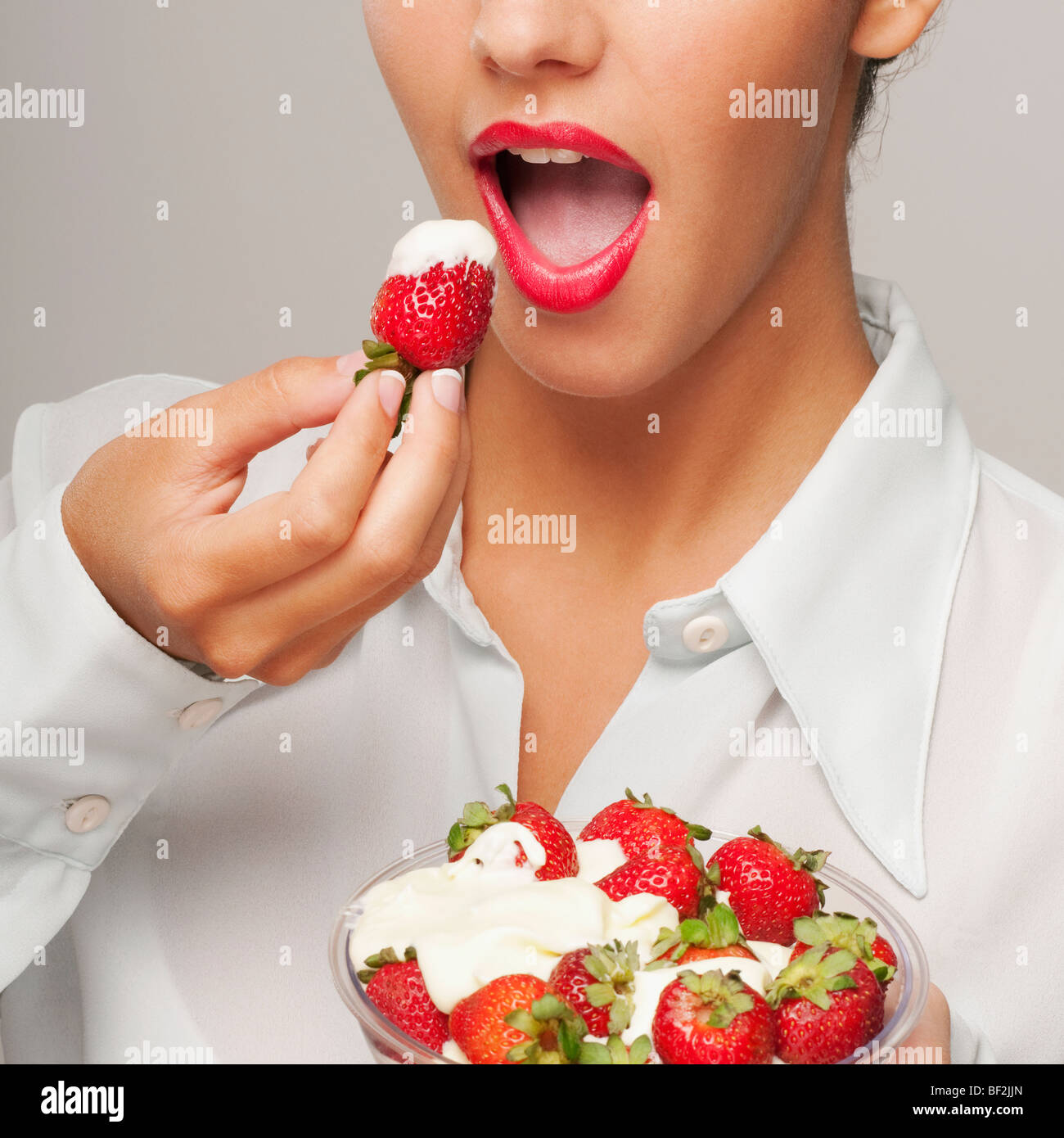 Close-up of a woman eating strawberries in cream Stock Photo - Alamy