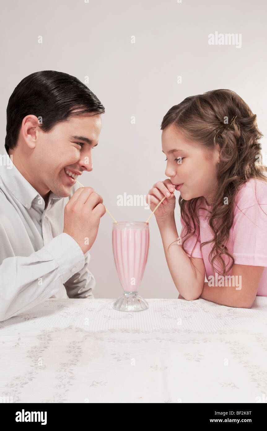 Side profile of a father and daughter sharing a milkshake Stock Photo ...