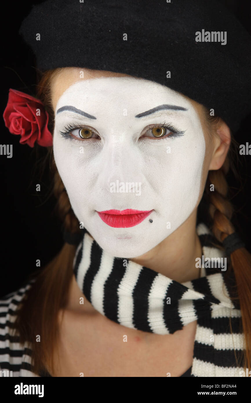Portrait of a young lady dressed up as a mime isolated over black ...