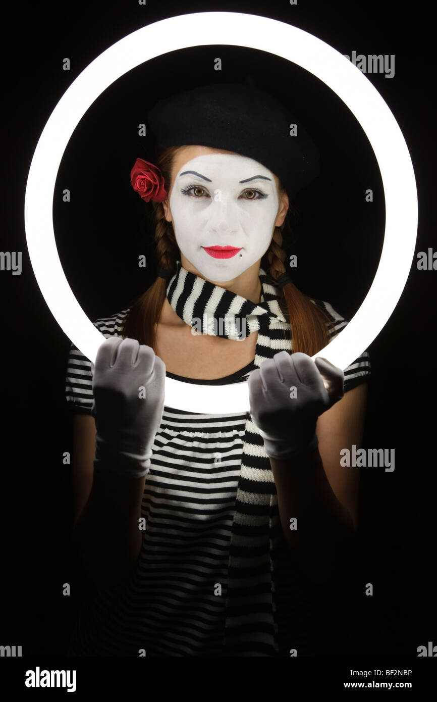 Portrait of a young lady dressed up as a mime isolated over black ...