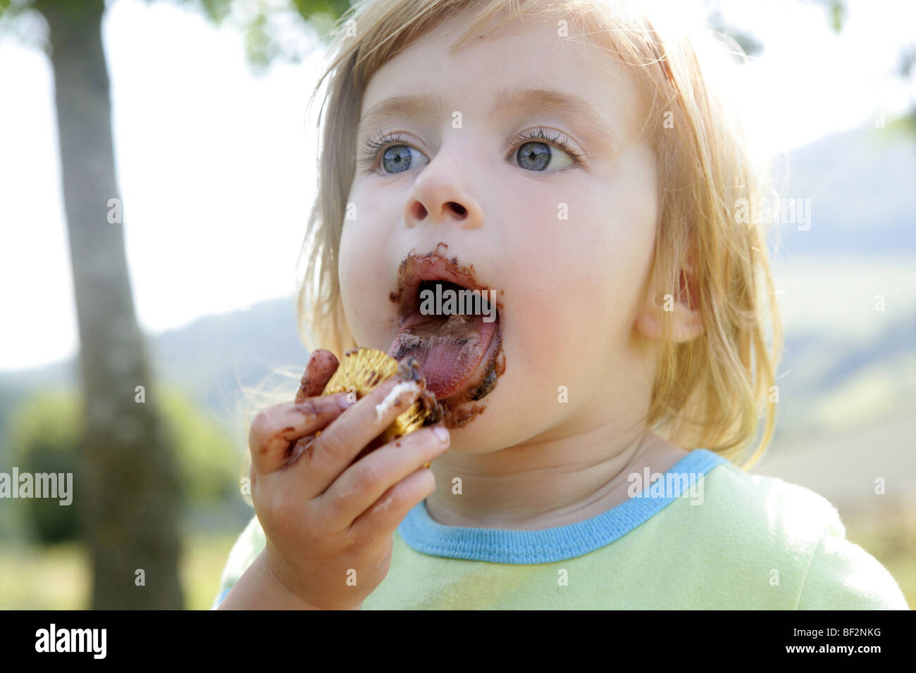 Adorable little girl eating chocolate outdoor field Stock Photo - Alamy