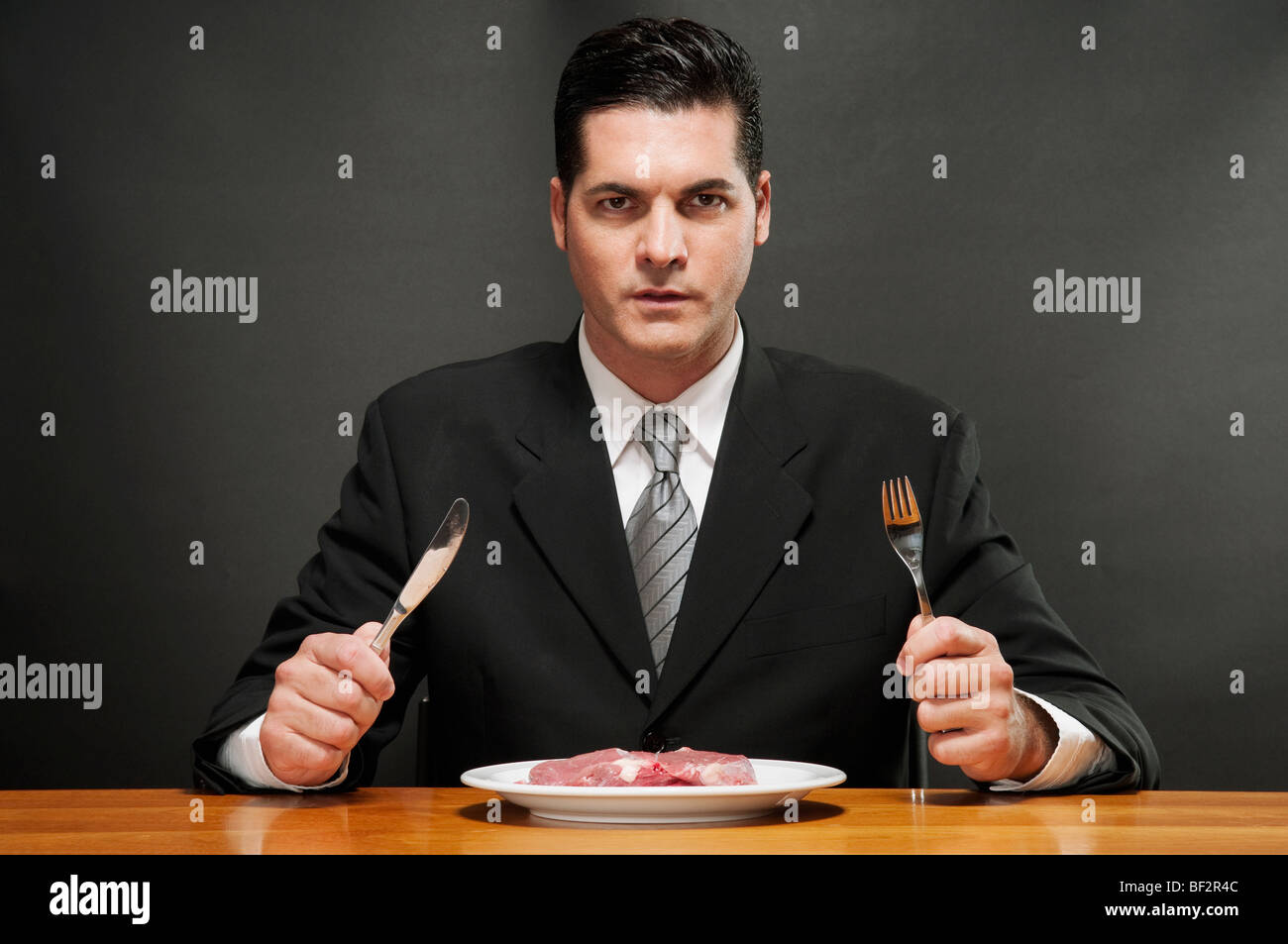Businessman eating a raw steak Stock Photo - Alamy