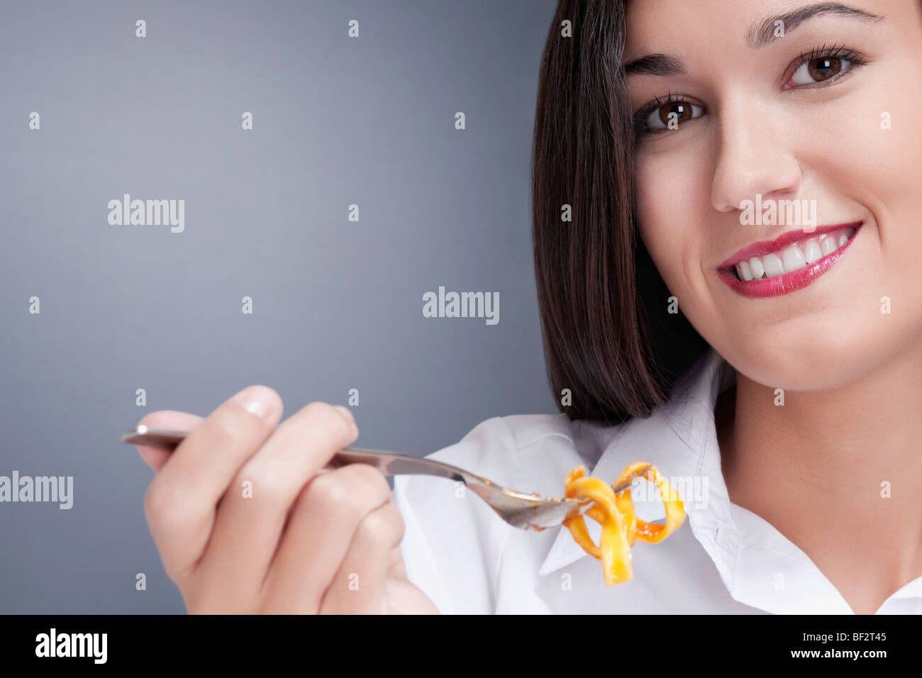 Woman eating pasta and smiling Stock Photo - Alamy