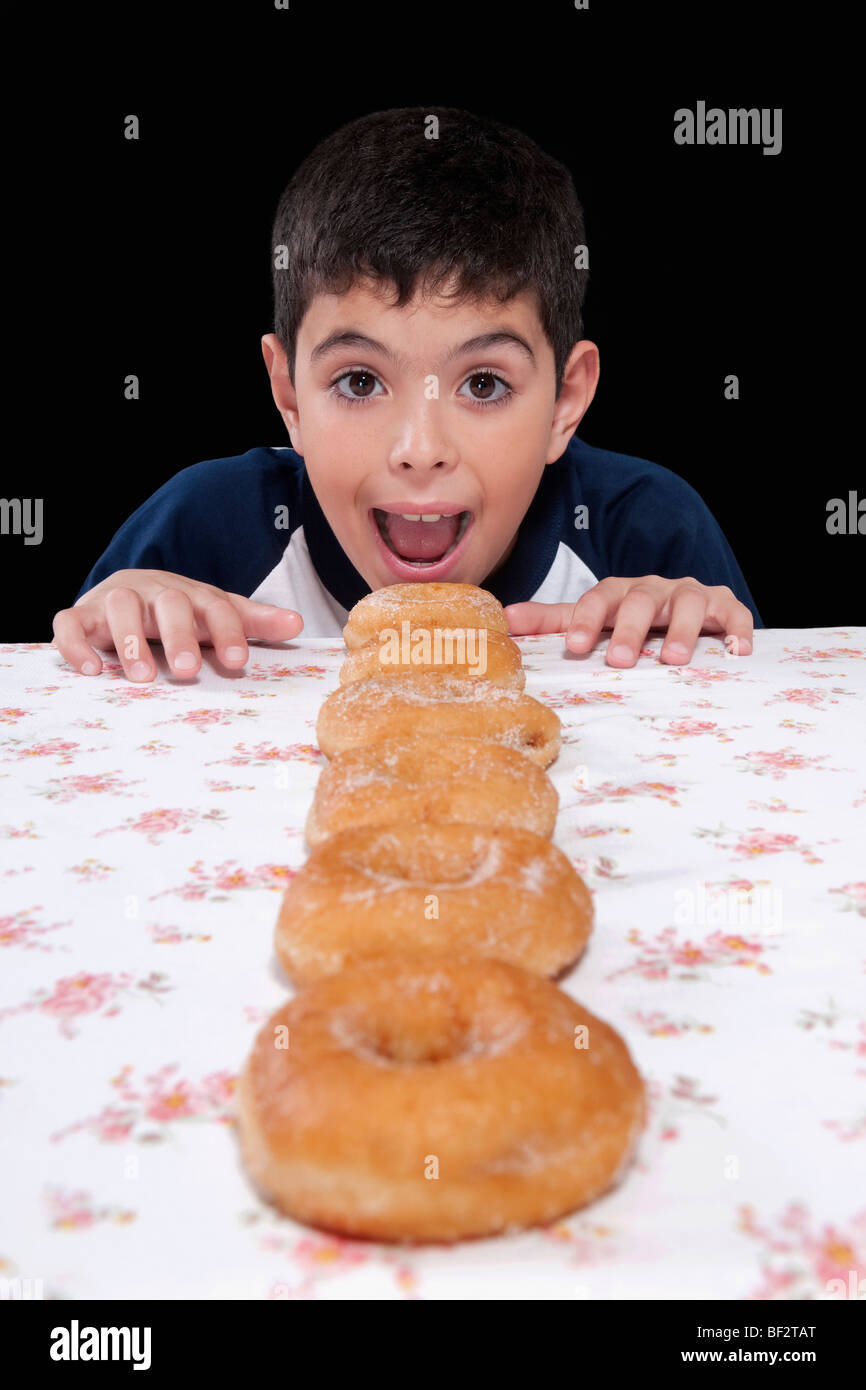 Boy with a row of donuts at a table Stock Photo - Alamy
