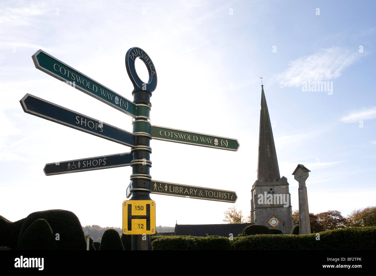 A signpost for the Cotswold Way, and the church of in the village of ...