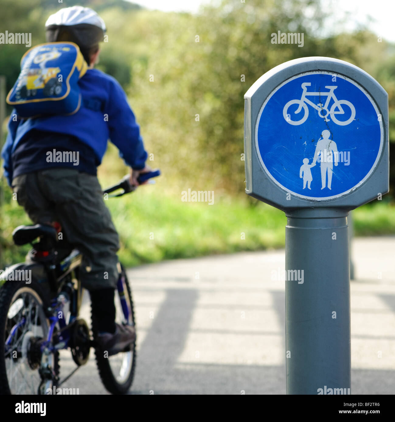 Rear view of a young Child cycling to school on dedicated cycle path ...