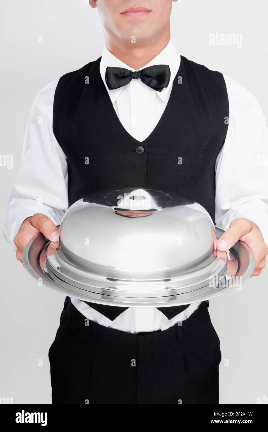 Waiter holding a covered dish Stock Photo - Alamy