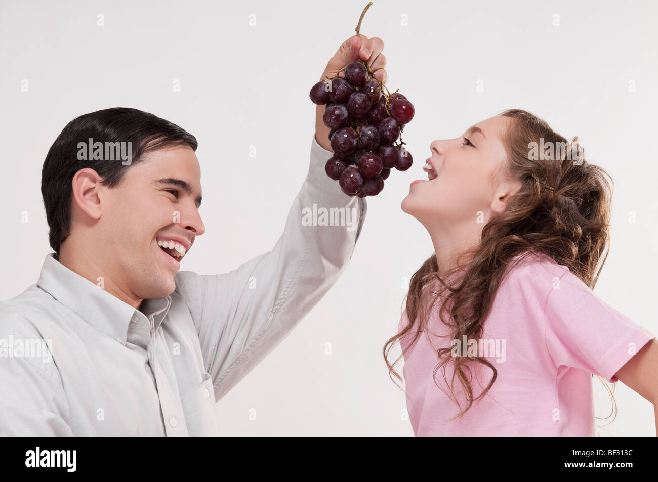 Man eating grapes to her daughter Stock Photo - Alamy