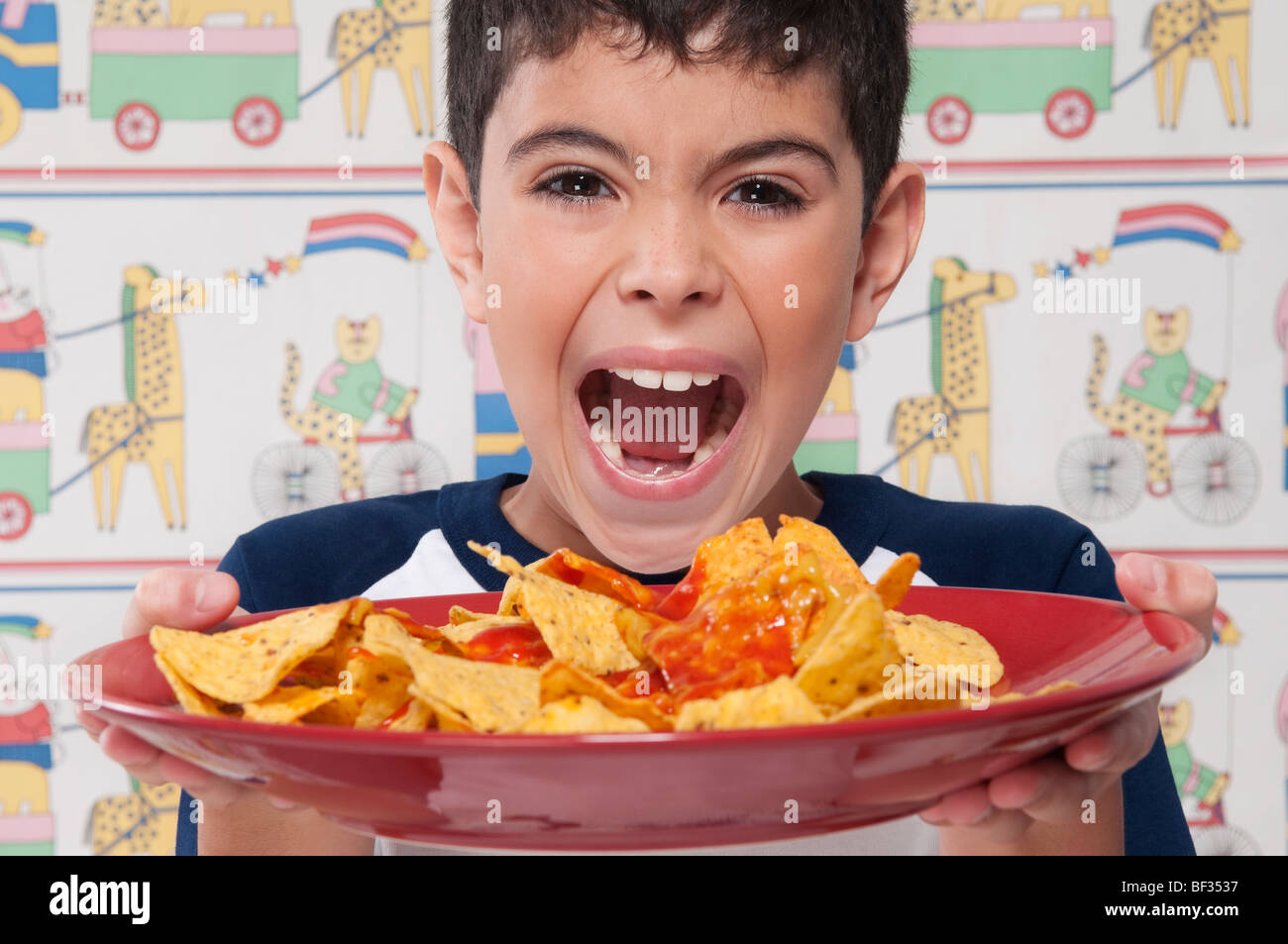 Portrait of a boy holding a platter of nachos and shouting in ...