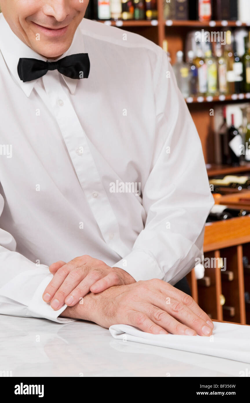 Waiter leaning against a bar counter Stock Photo - Alamy