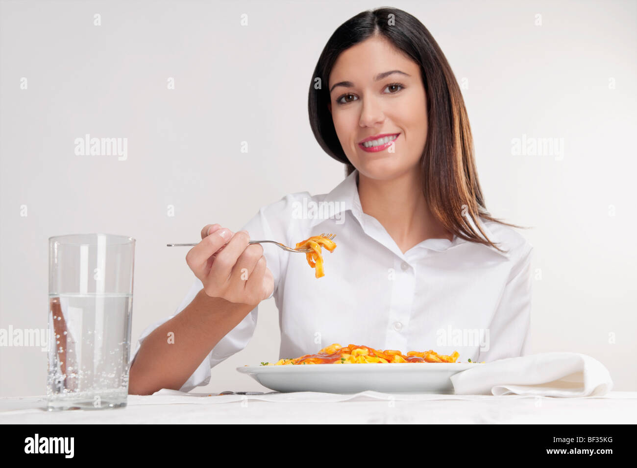 Woman eating pasta and smiling Stock Photo - Alamy