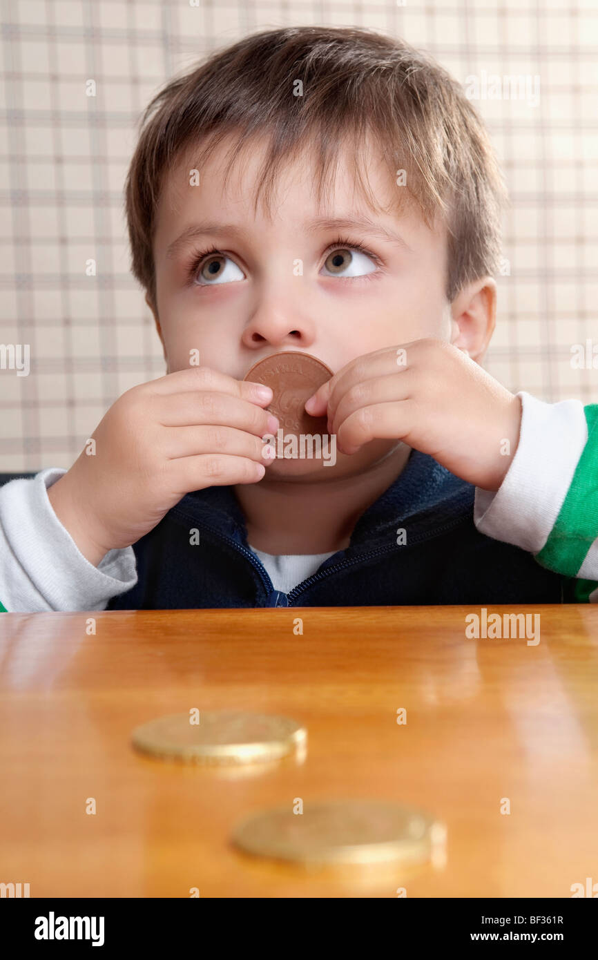Boy eating chocolate cookie while holding hi-res stock photography and ...