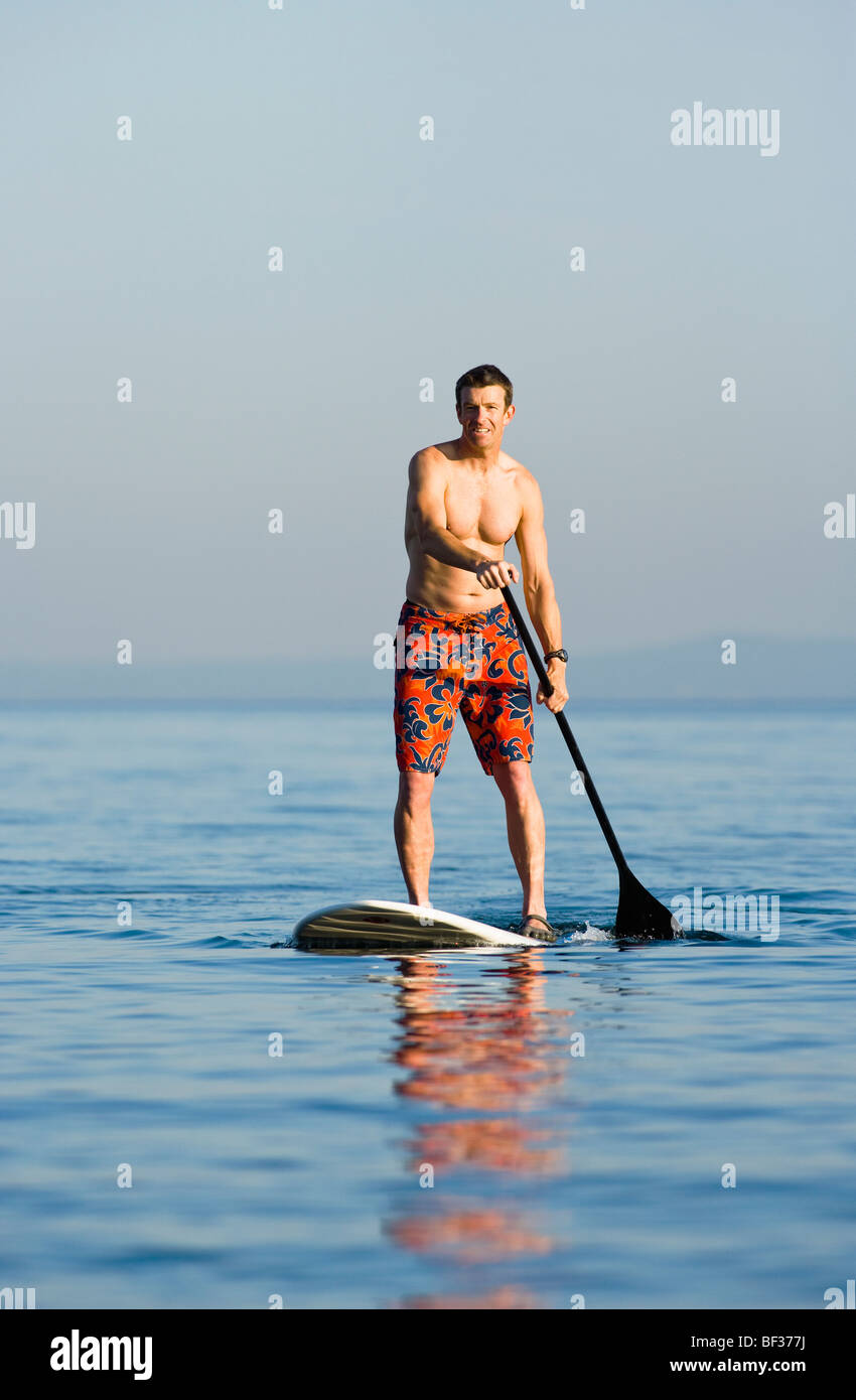 A late 30's Caucasian man on a stand up paddle board on the Puget Sound ...