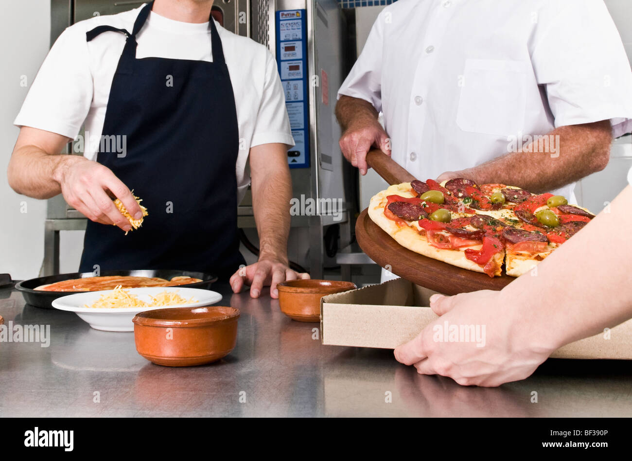 Three chefs preparing pizza in the kitchen Stock Photo - Alamy