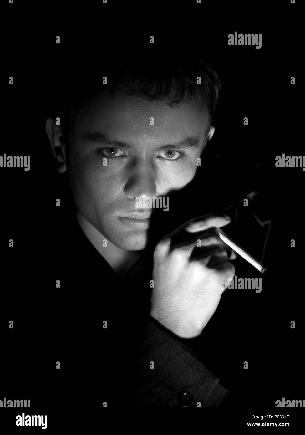Young man in suit smoking cigarette looking into camera Stock Photo - Alamy