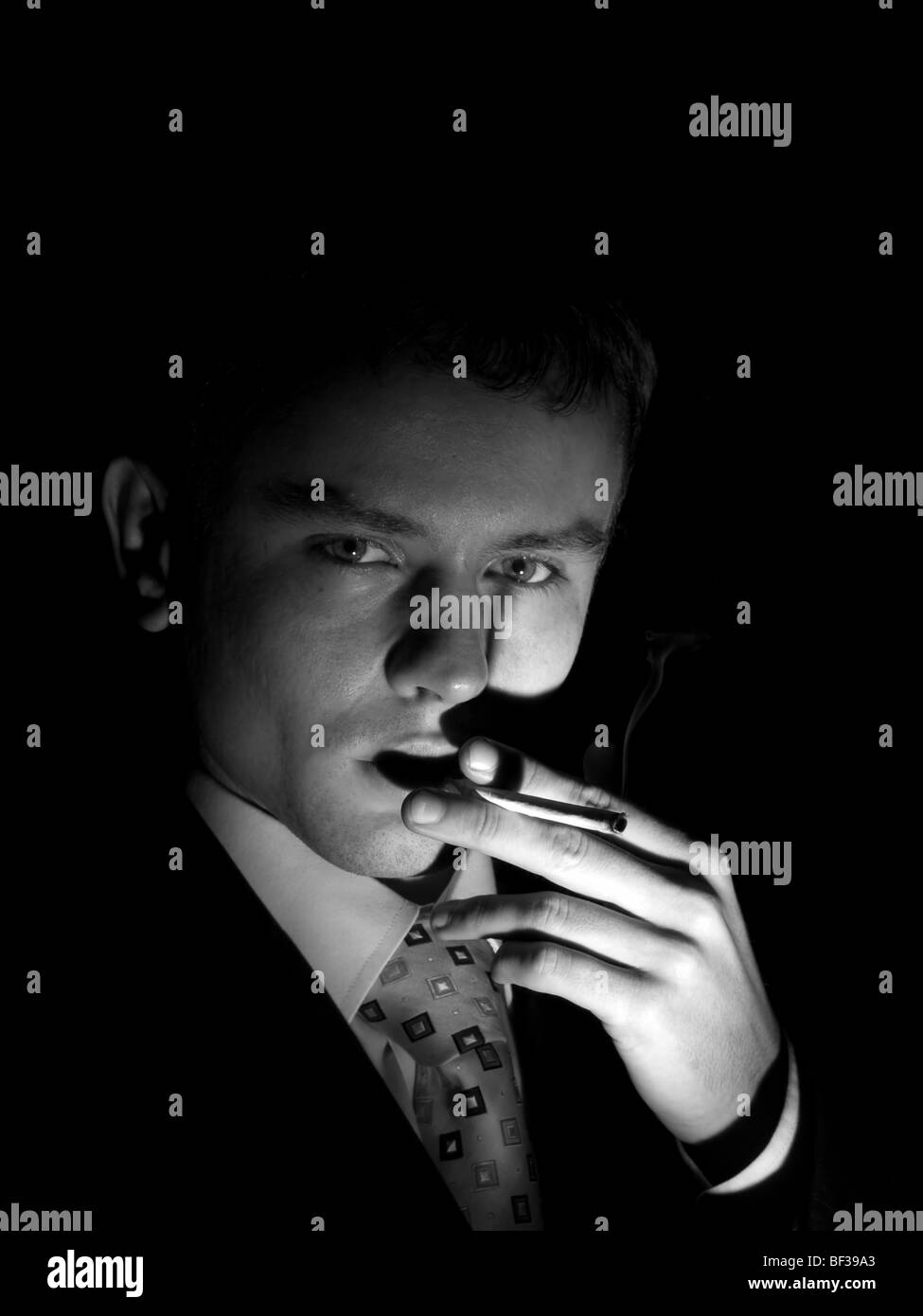 Young man in suit smoking cigarette looking into camera Stock Photo - Alamy