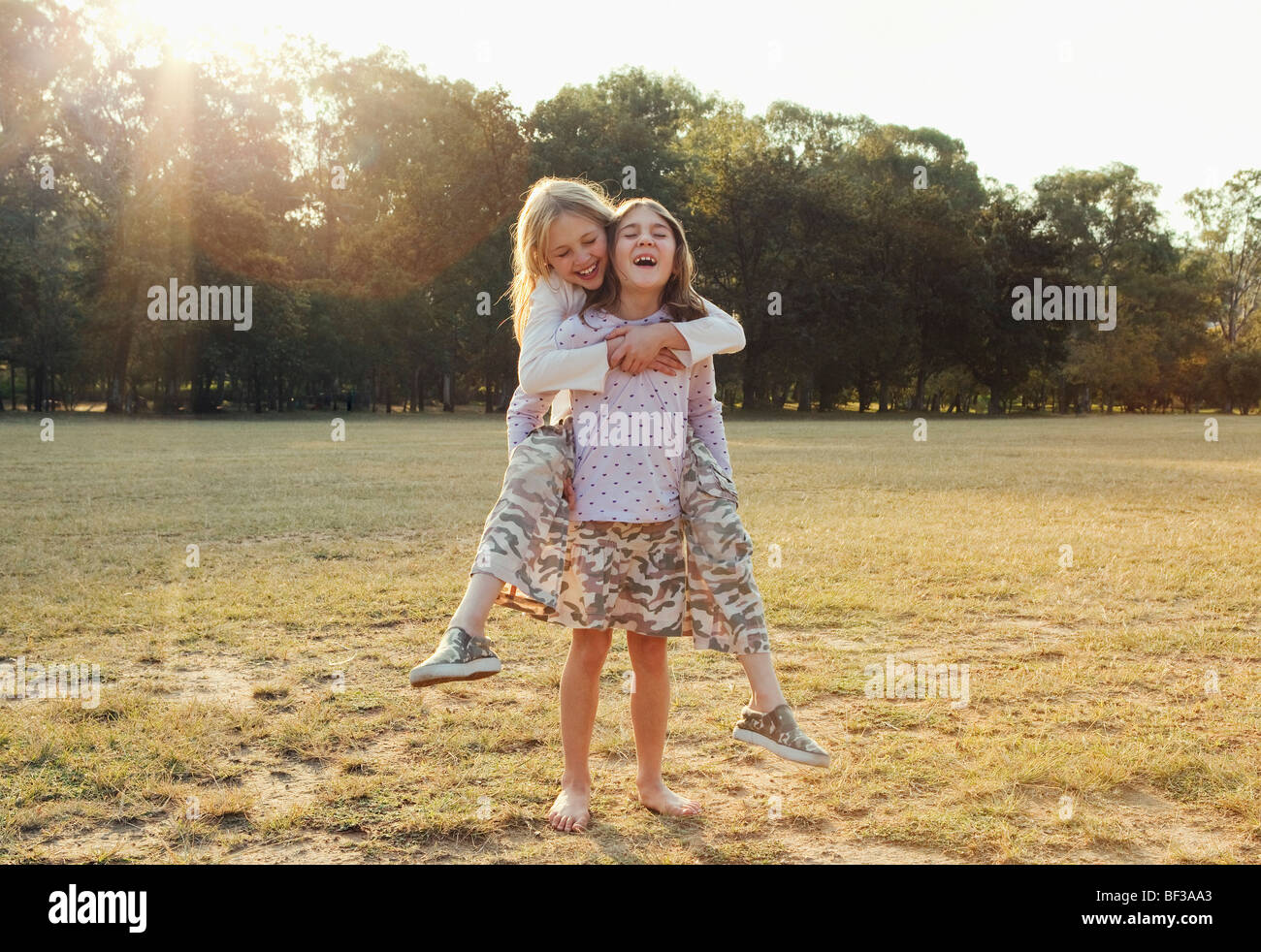 Girl getting piggyback from sister Stock Photo - Alamy
