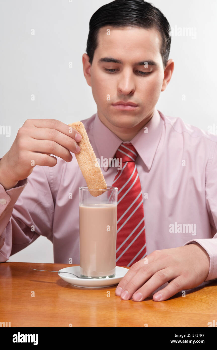 Businessman dipping a wafer into milk Stock Photo - Alamy