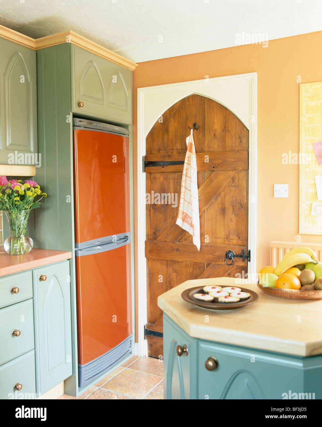 Red fridge-freezer beside wooden Gothic-style door in traditional ...