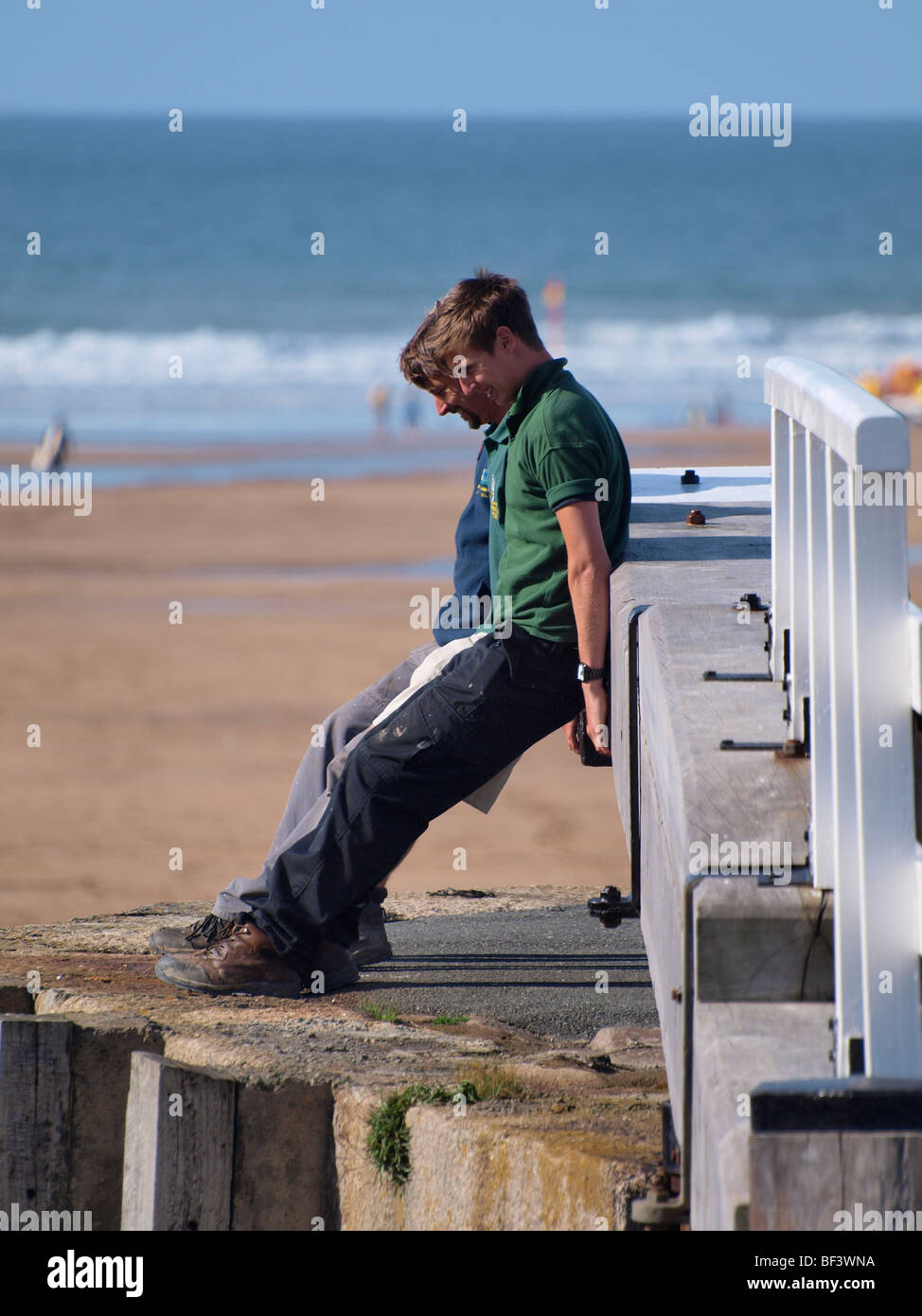 Three men pushing open lock gate to allow yacht out to sea, Bude ...