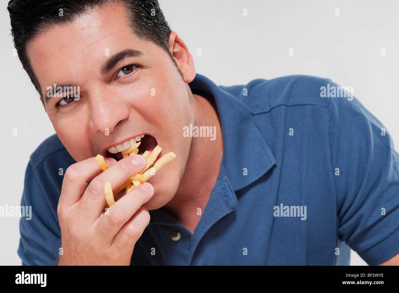 Portrait of a man eating French fries Stock Photo - Alamy