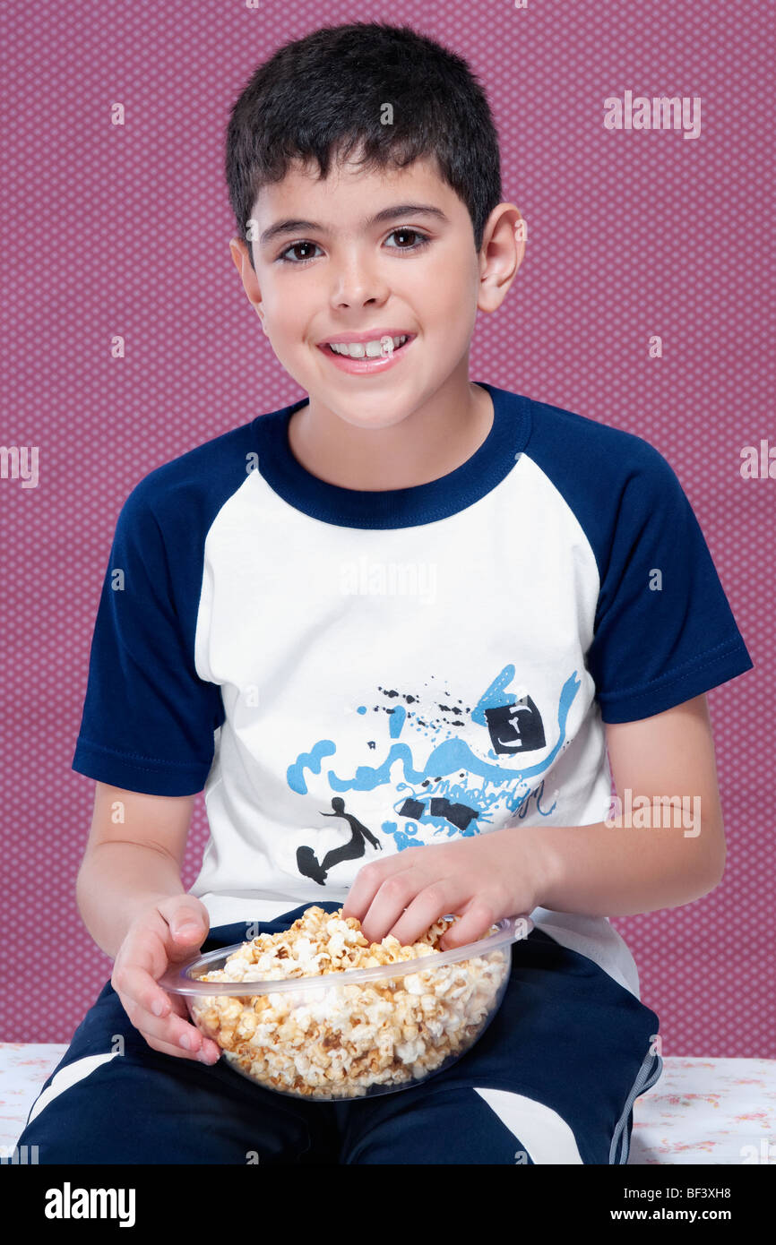 Boy holding a bowl of popcorn and smiling Stock Photo - Alamy