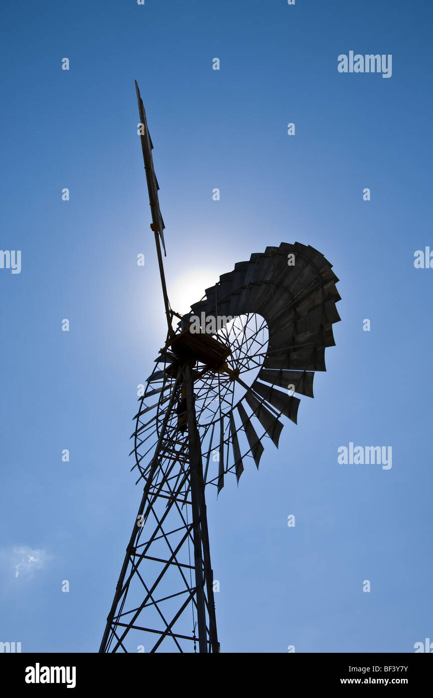 An old farm windmill with the sun behind it, against a blue sky Stock ...