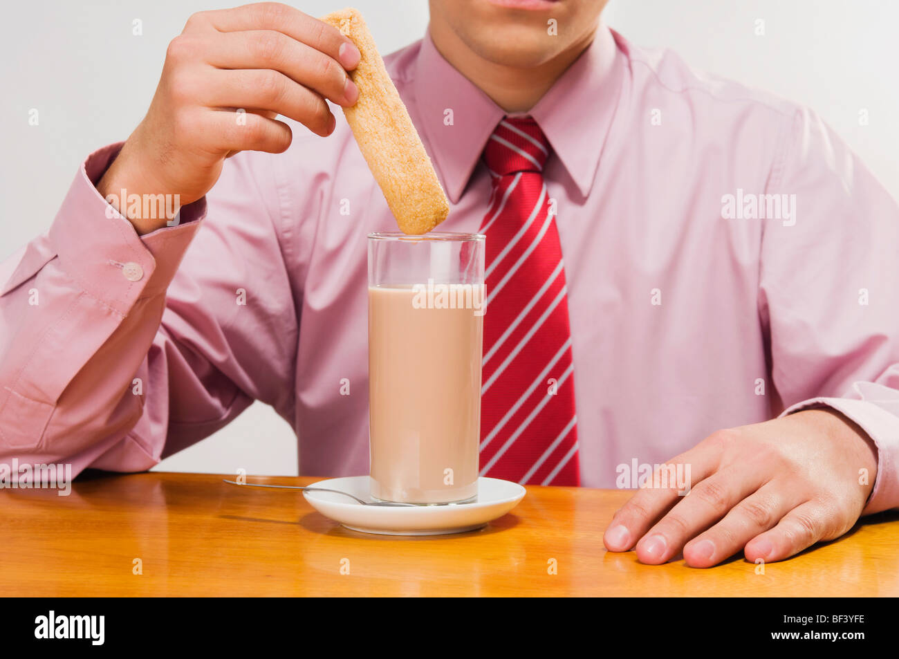 Mid section view of a businessman dipping a wafer in milk Stock Photo ...