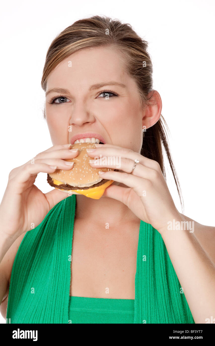 Cute Caucasian woman eating a cheeseburger over a white background ...