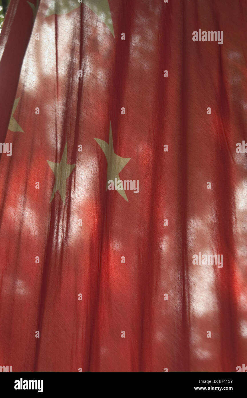 Close up of a Chinese flag hanging in the shadows from a doorway in a ...